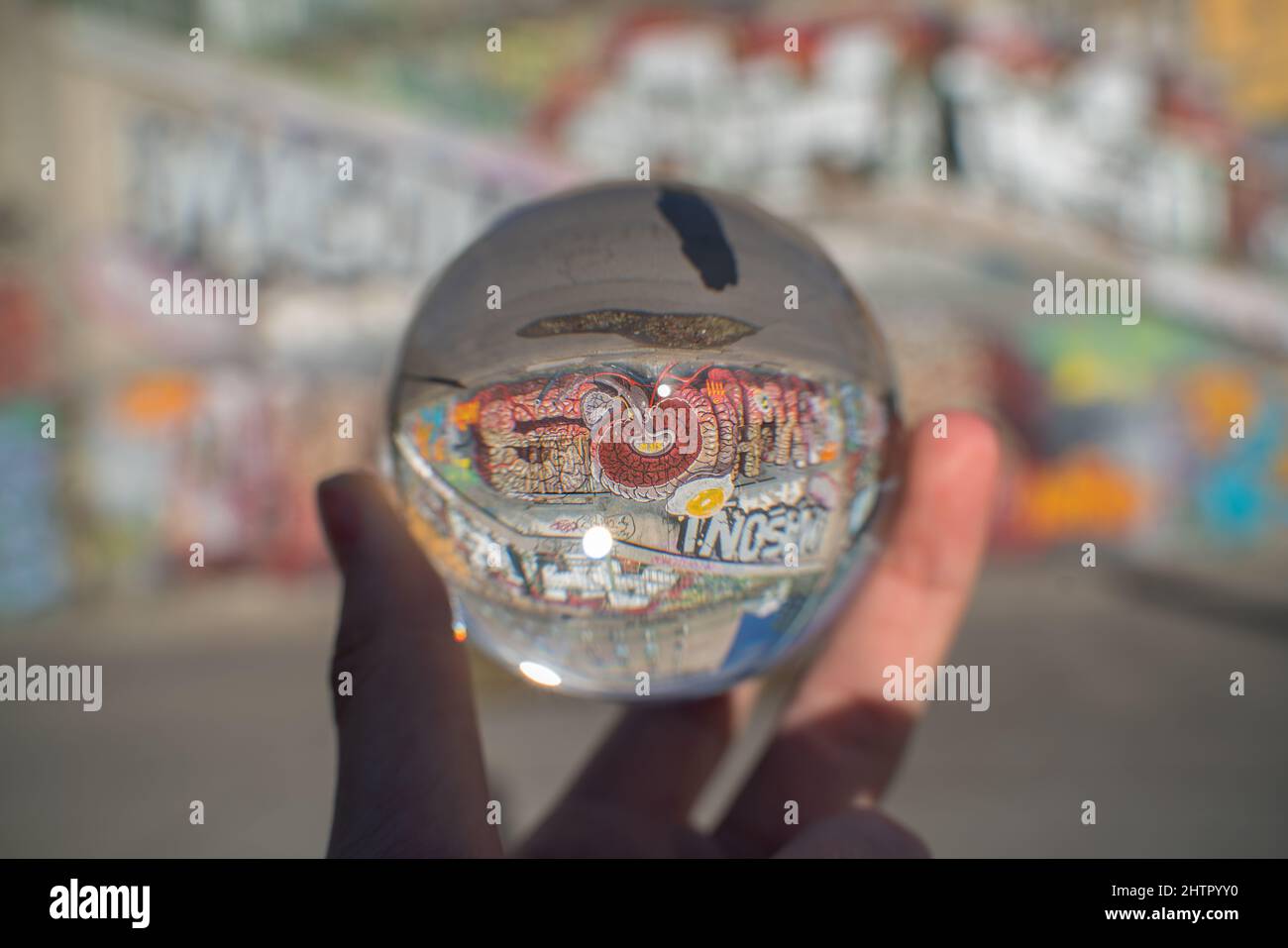 Hand holding a crystal ball with the reflection of graffiti street art ...