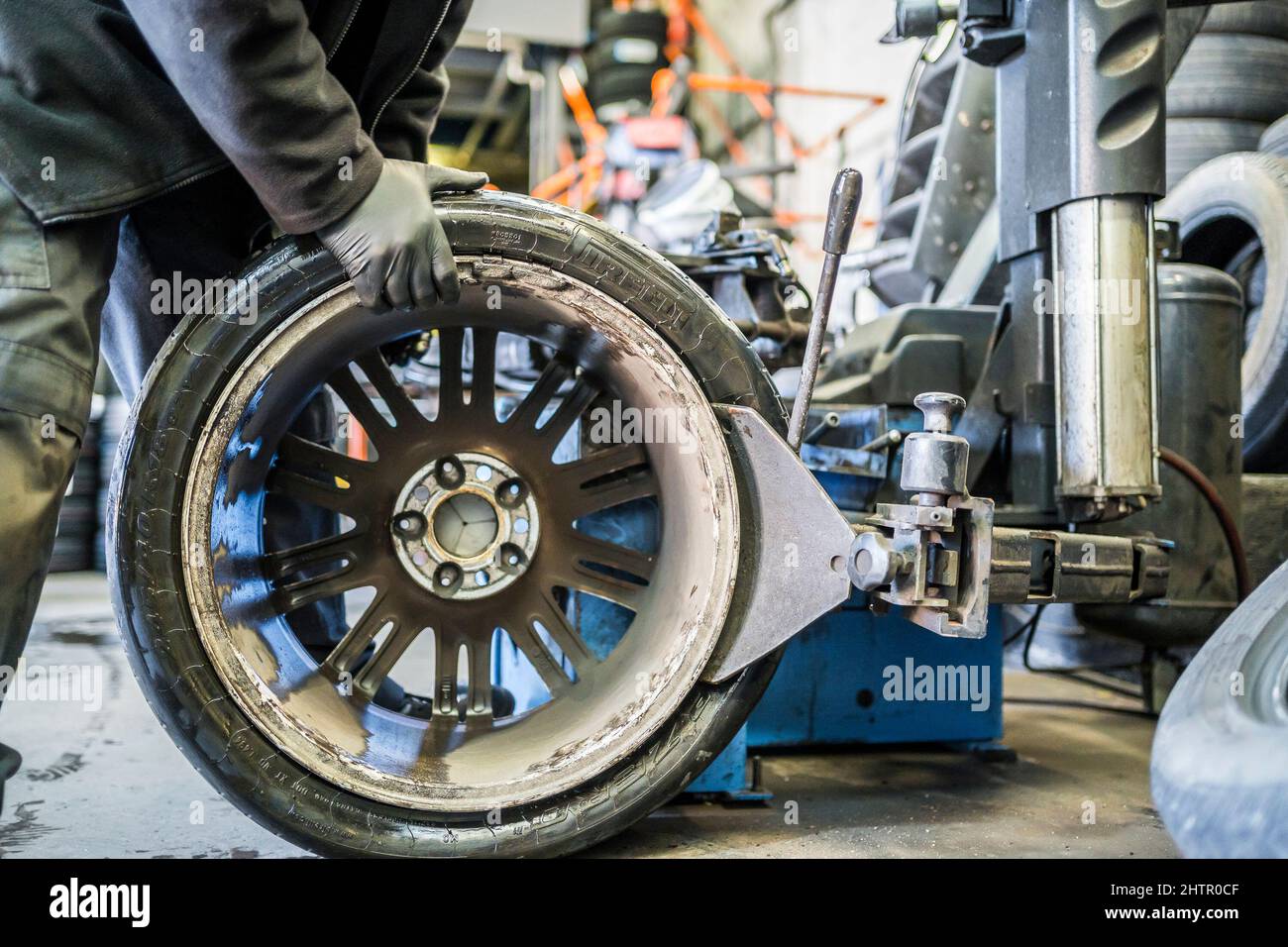 UK tyre garage workshop. Garage staff remove a tyre on an alloy wheel ...