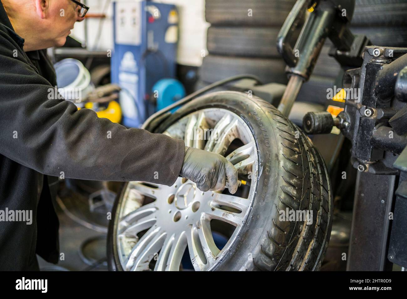 UK tyre garage workshop. Gararge mechanic inflates a car tyre on an ...
