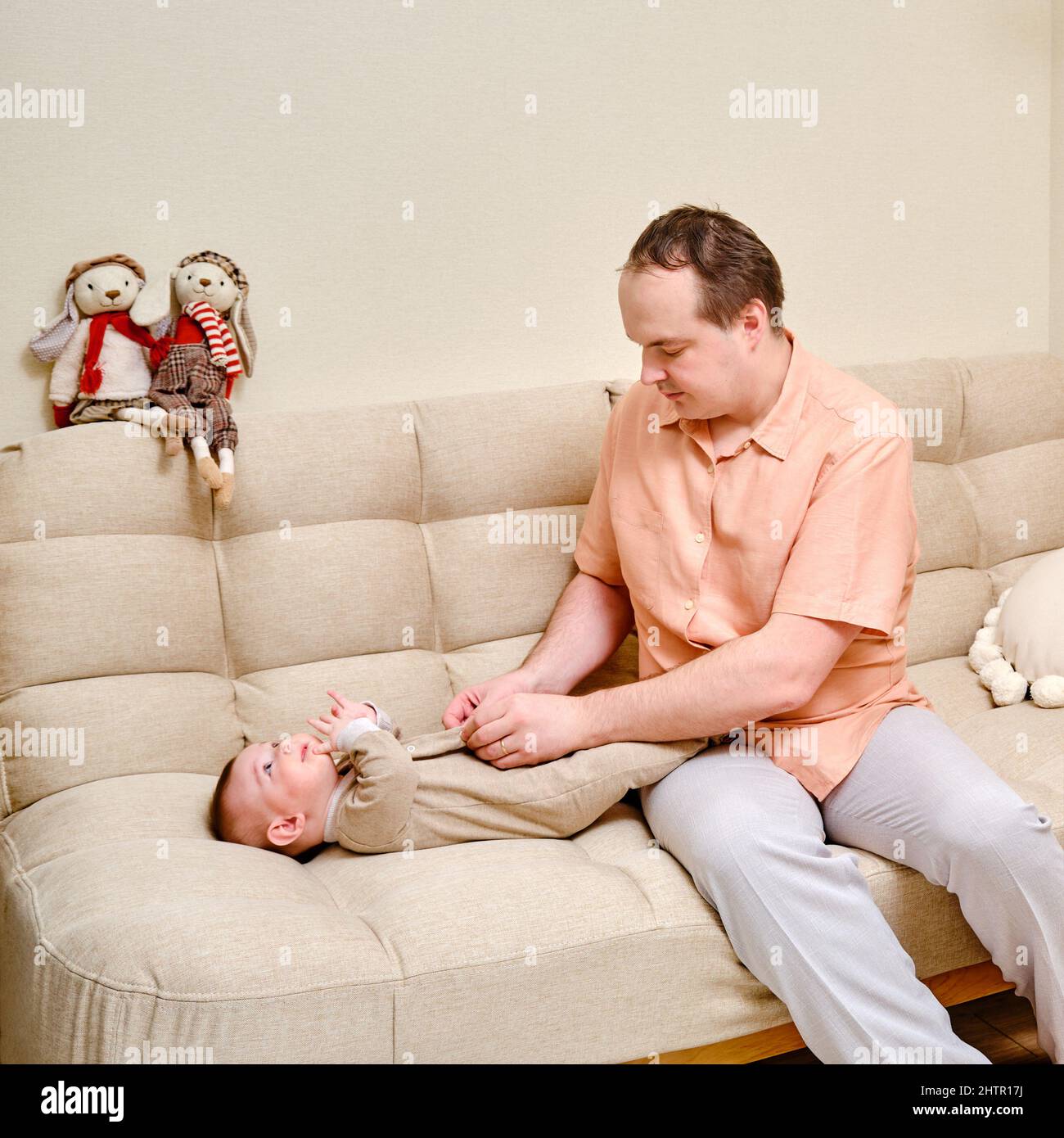 Man father putting clothes on boy son on sofa in home living room Stock ...
