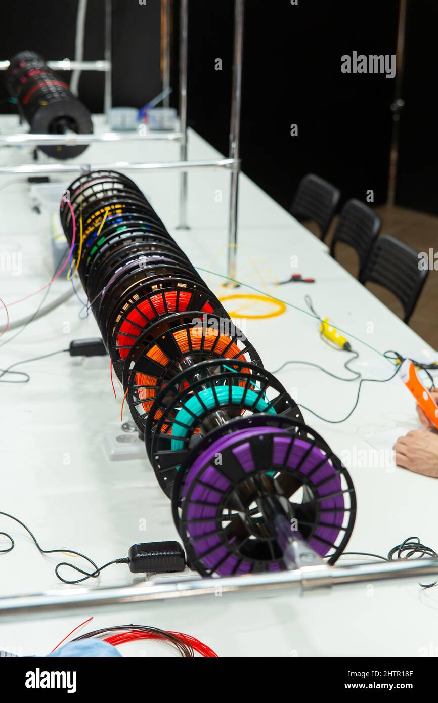 Colorful rainbow plastic filaments on bobbins and some 3D pens laying ...