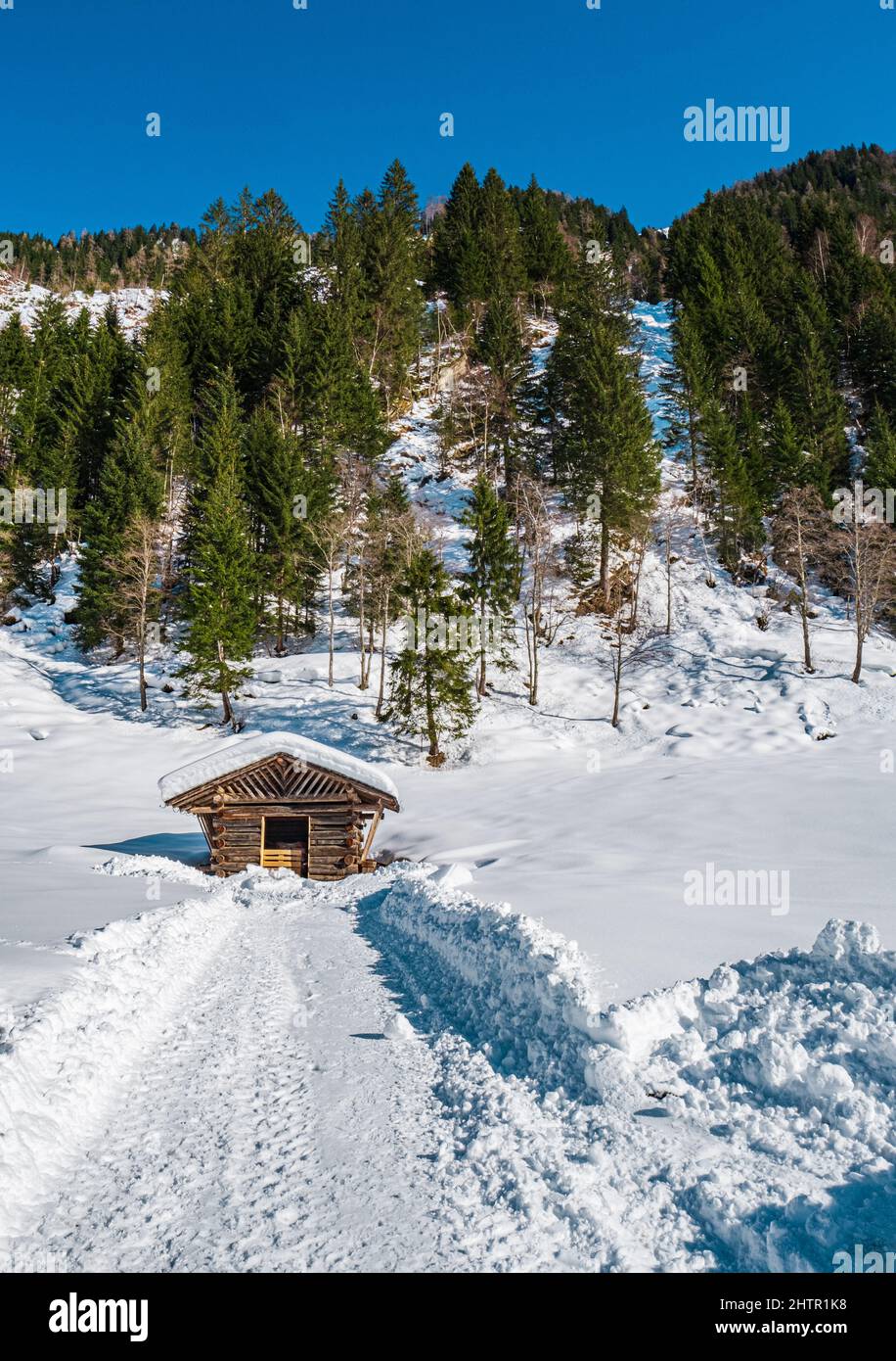 Wooden cabin in front of a wooded mountain with deep snow in a winter ...