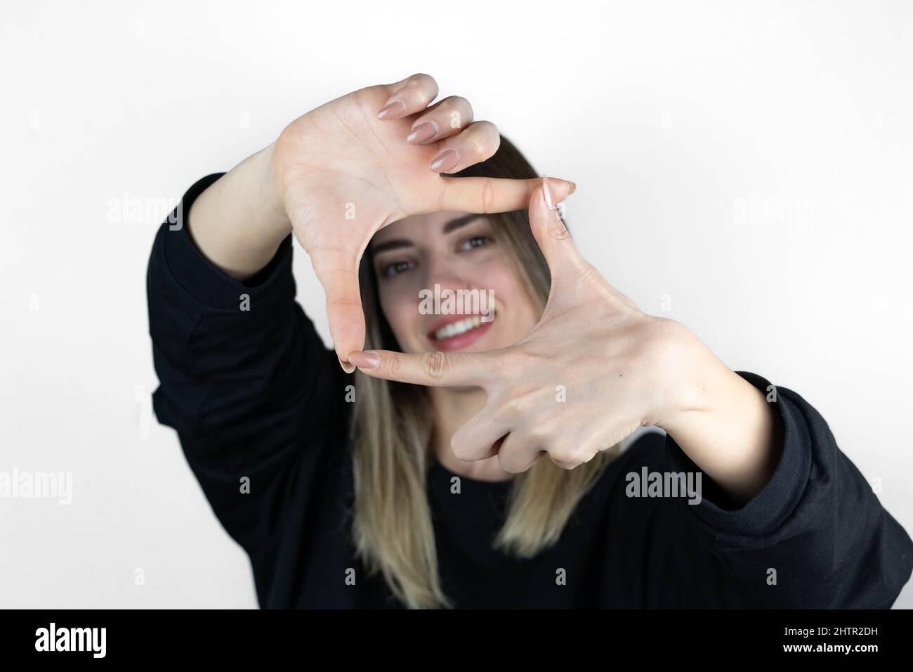 Happy girl looking through a frame formed by hands. Attractive girl ...