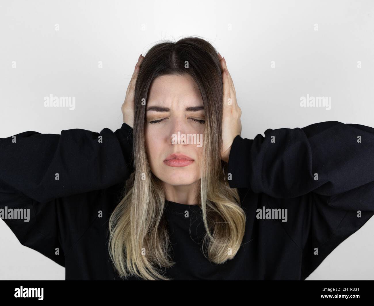 Frustrated girl covering her ears with her hands while screwing her ...