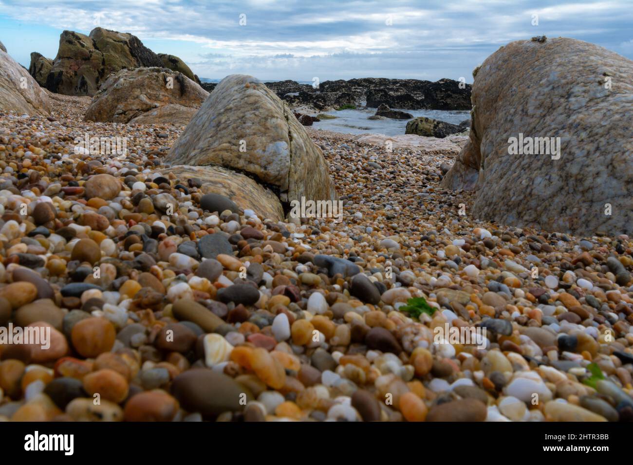 Scenic view of a beach with tiny rocks on cloudy sky background Stock ...