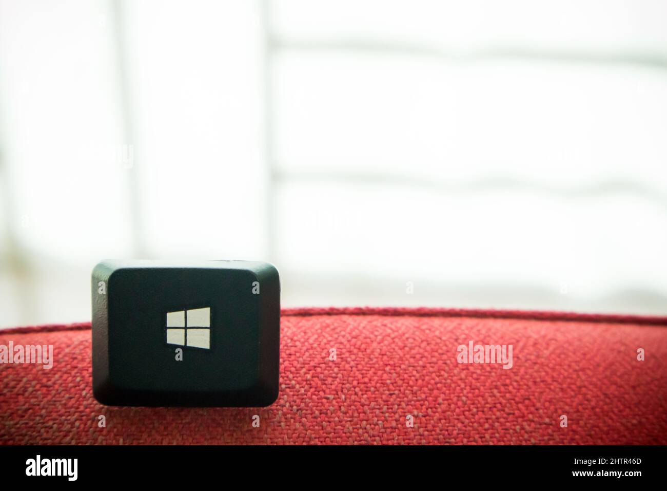 Windows start button of a keyboard in front of a window on a red ...