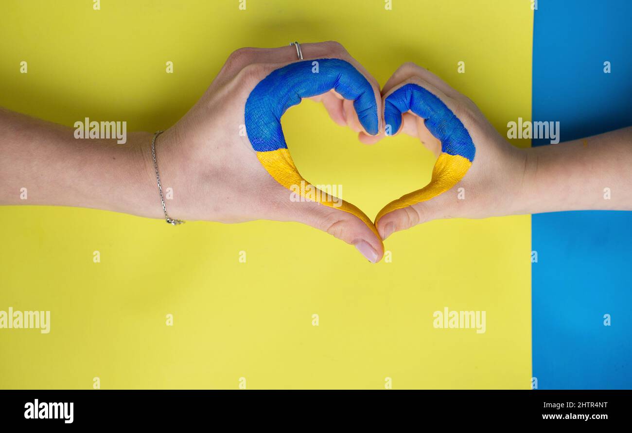 women's and children's hands join in shape of a heart painted in yellow ...