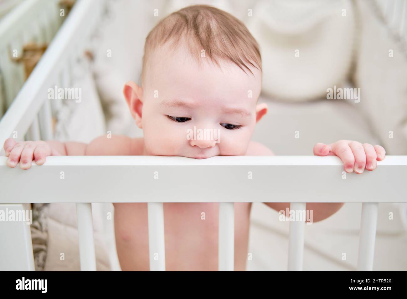 Baby gnaws at the edge crib during teething itching. Funny child ...