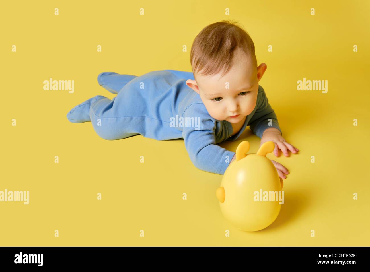 Curious toddler baby crawling on studio yellow background. Funny child ...