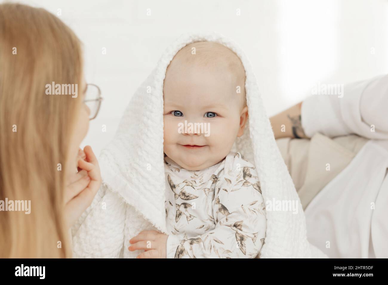 Portrait of beautiful smiling blue-eyed plump baby infant covered with ...