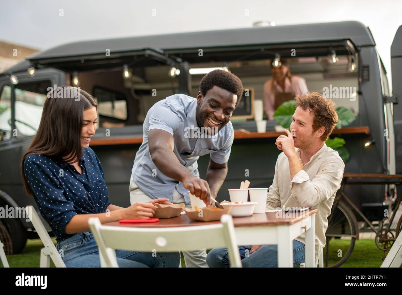 Happy diverse friends eating fast food near truck Stock Photo - Alamy