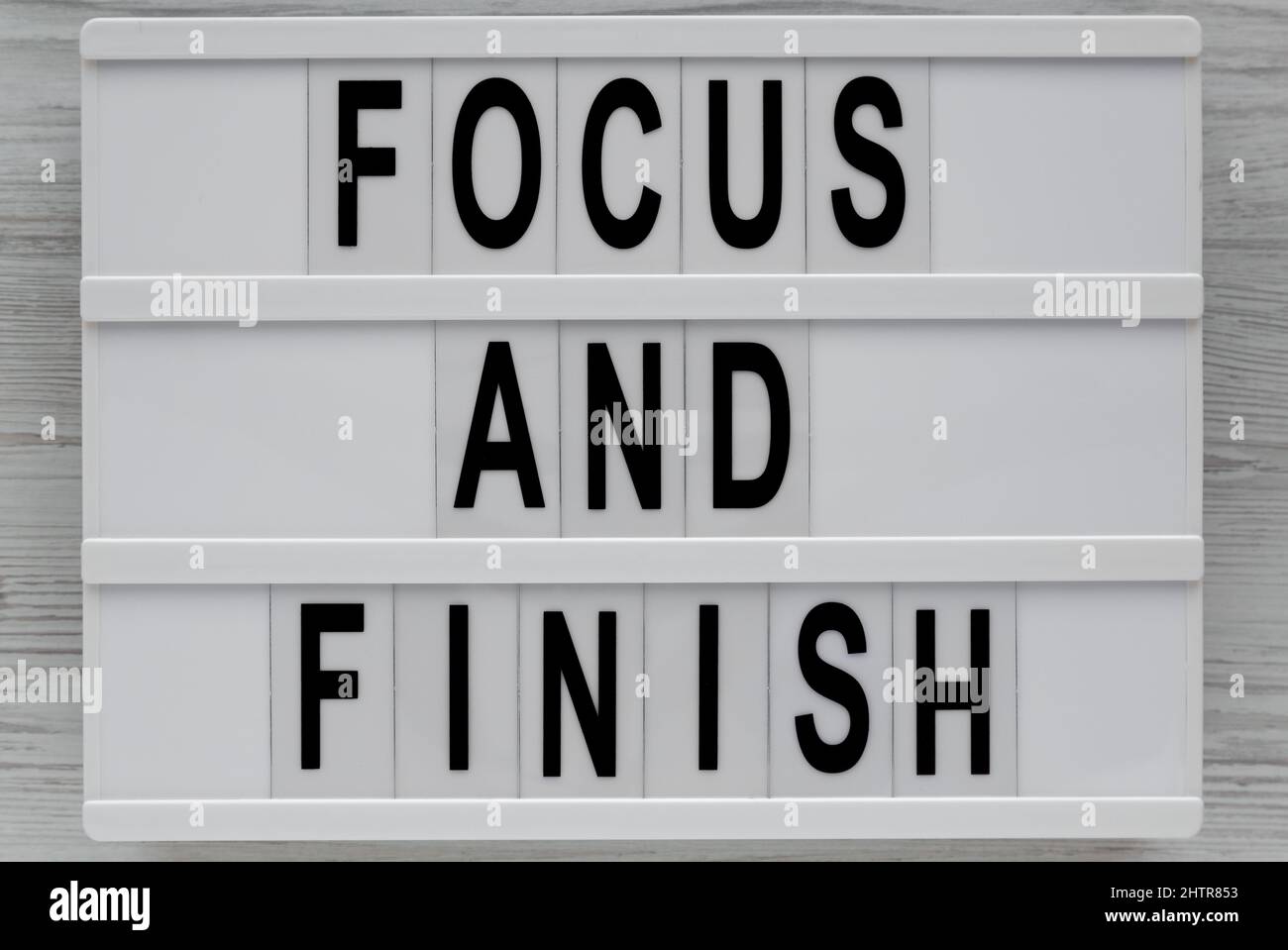 'Focus and Finish' on a lightbox on a white wooden background, top view ...