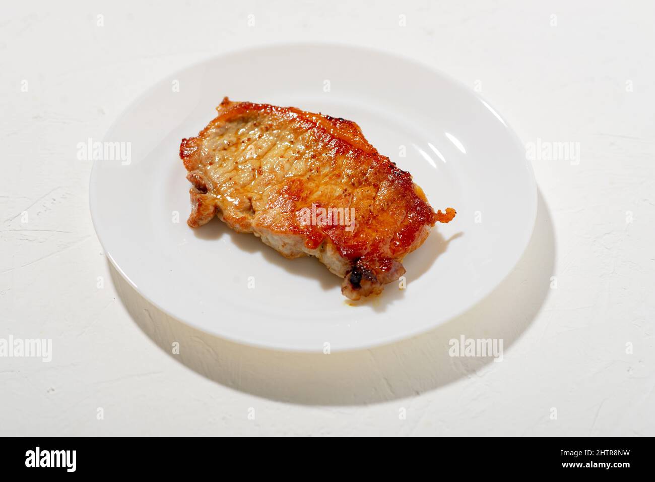 A piece of fried meat on a white plate. Bad fatty food. White ...