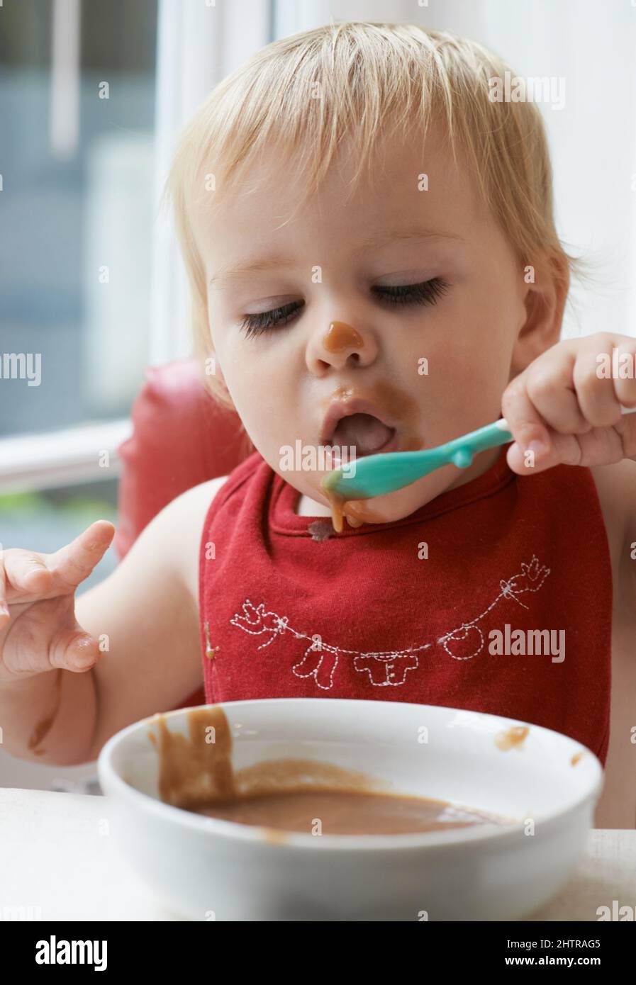 Really enjoying my meal. A baby feeding herself Stock Photo - Alamy