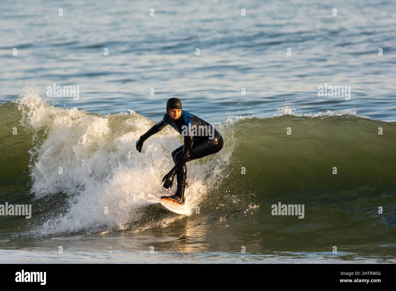 View of surfer dissecting ocean waves in a special suit in Emerald Isle ...