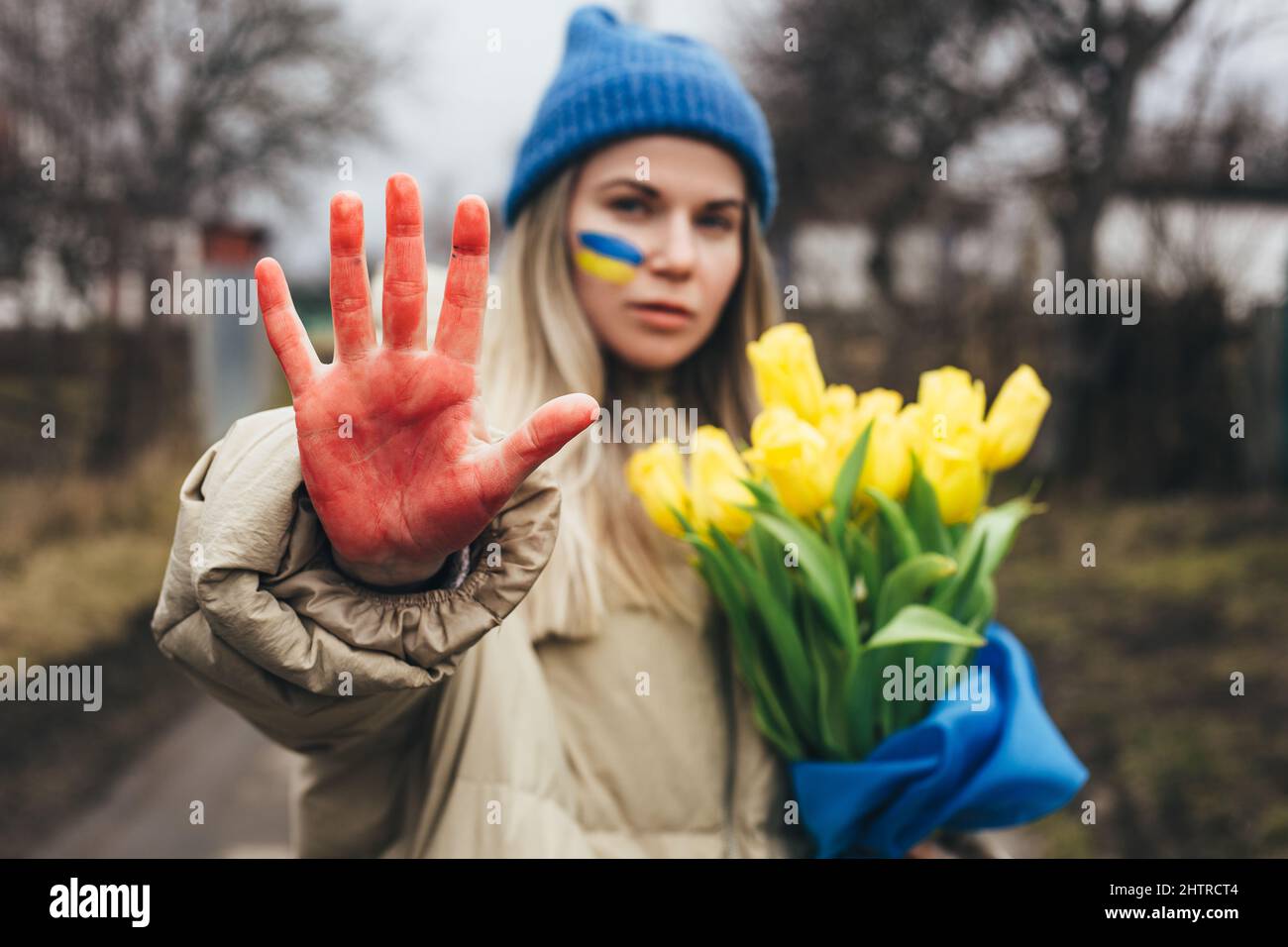 Portrait of young beautiful woman with flowers and Ukrainian flag. Stop ...