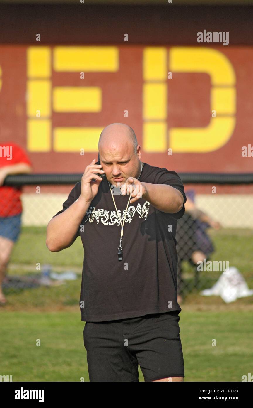 Shaved head football coach for little guys in full uniforms and pads ...