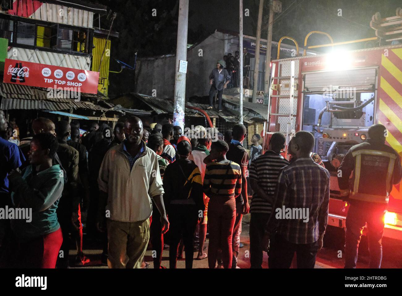 Residents watch from a distance as firefighters struggle to put out a ...
