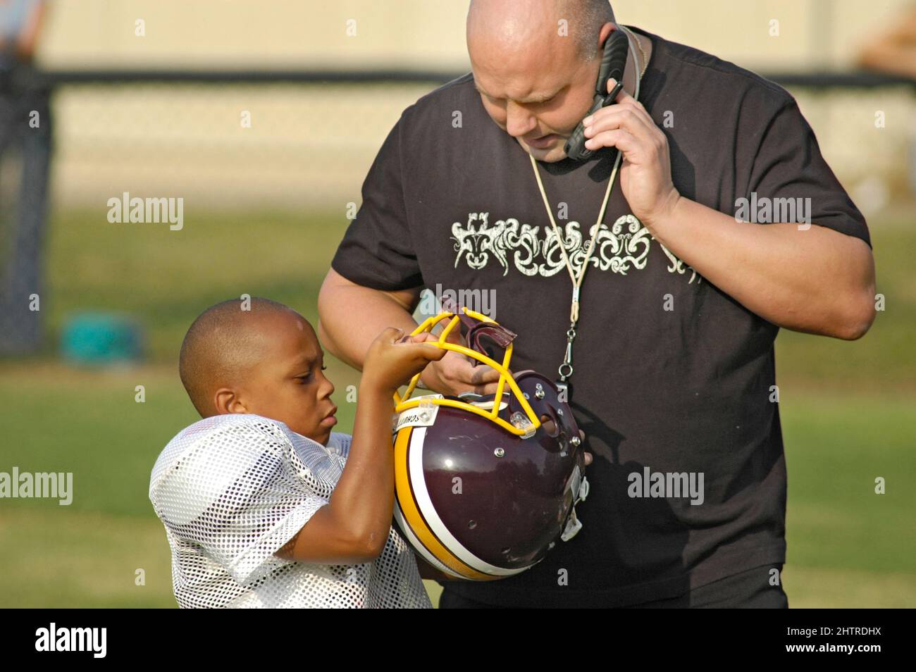 Shaved head football coach for little guys in full uniforms and pads ...