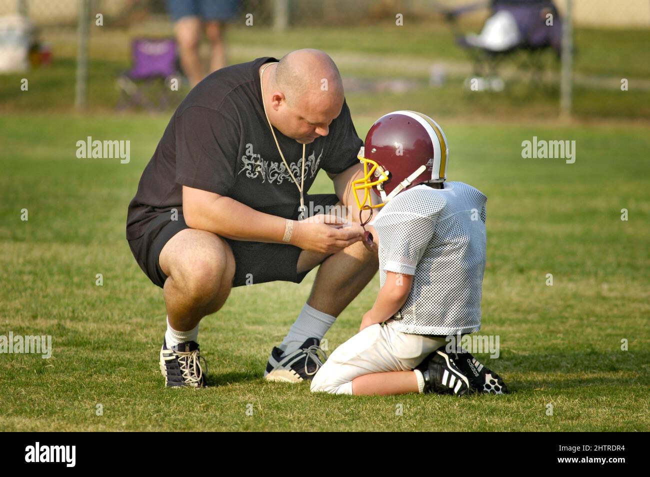 Shaved head football coach for little guys in full uniforms and pads ...