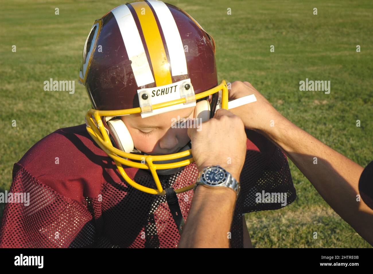 Shaved head football coach for little guys in full uniforms and pads ...