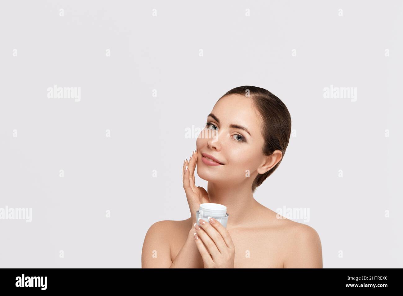 Beautiful young woman with clean fresh skin. Girl holding cream in her ...