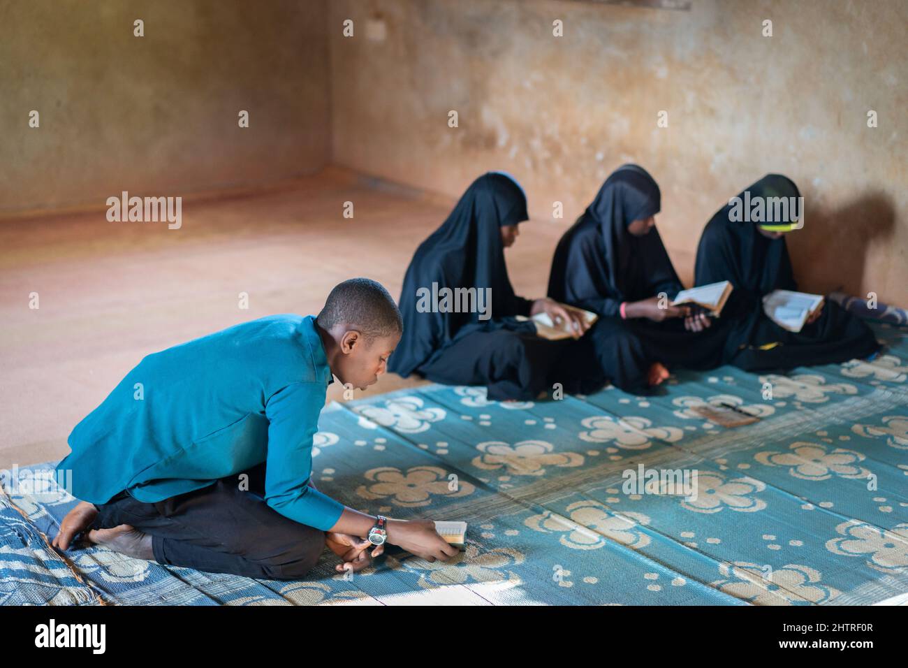 African teenage boys and girls sitting and reading book in poor school ...