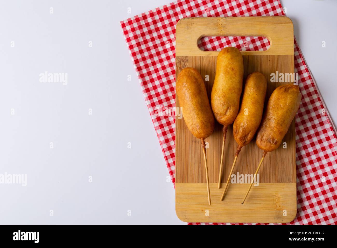 Corn dogs served on serving board with checked pattern napkin over ...