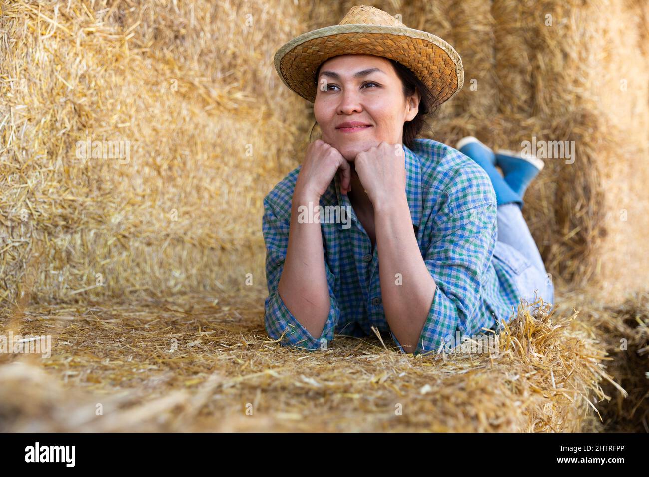 Female farmer posing in the barn against backdrop of hay bales Stock ...
