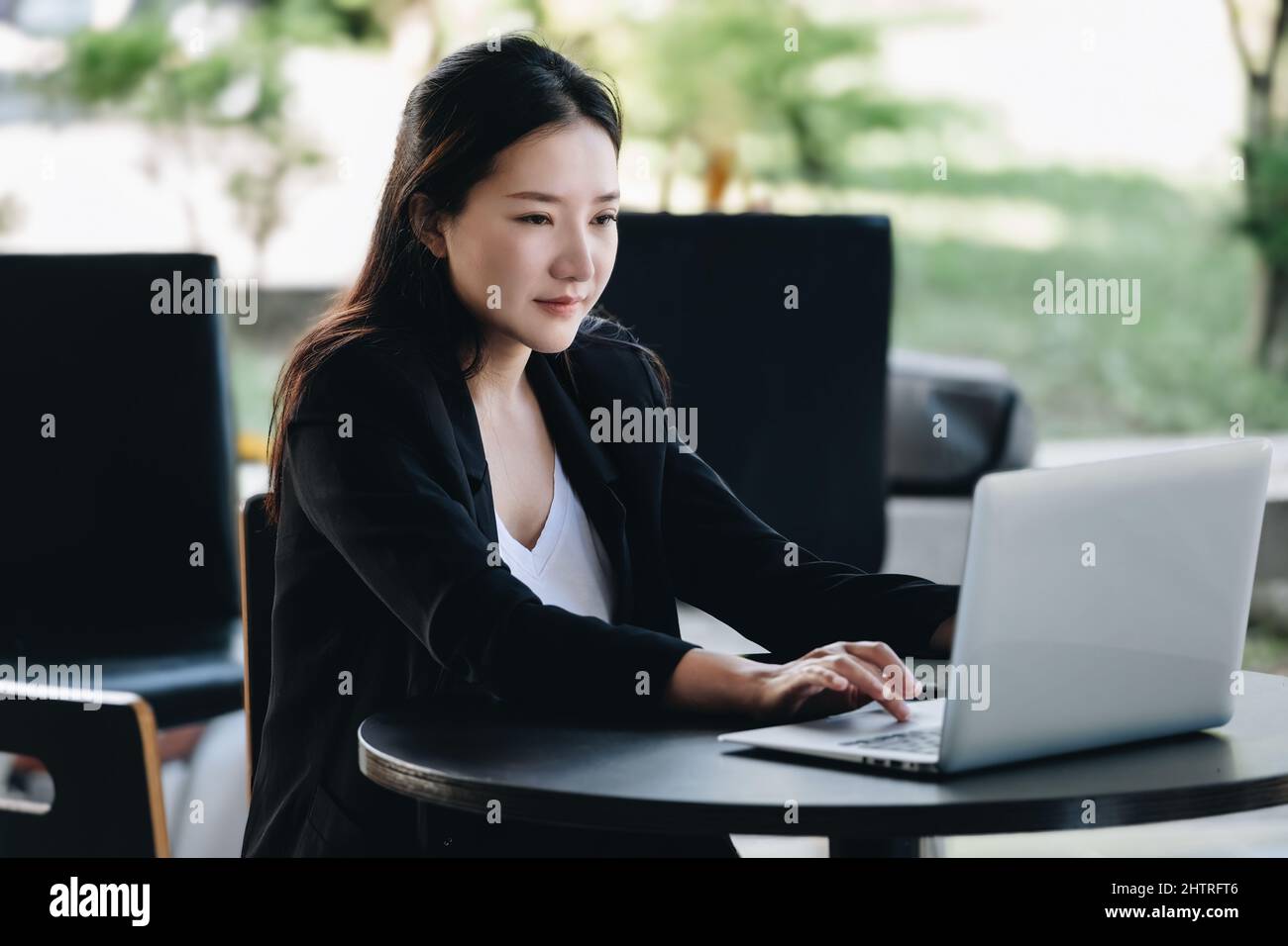 A female worker smiling happily while using a computer in the office ...