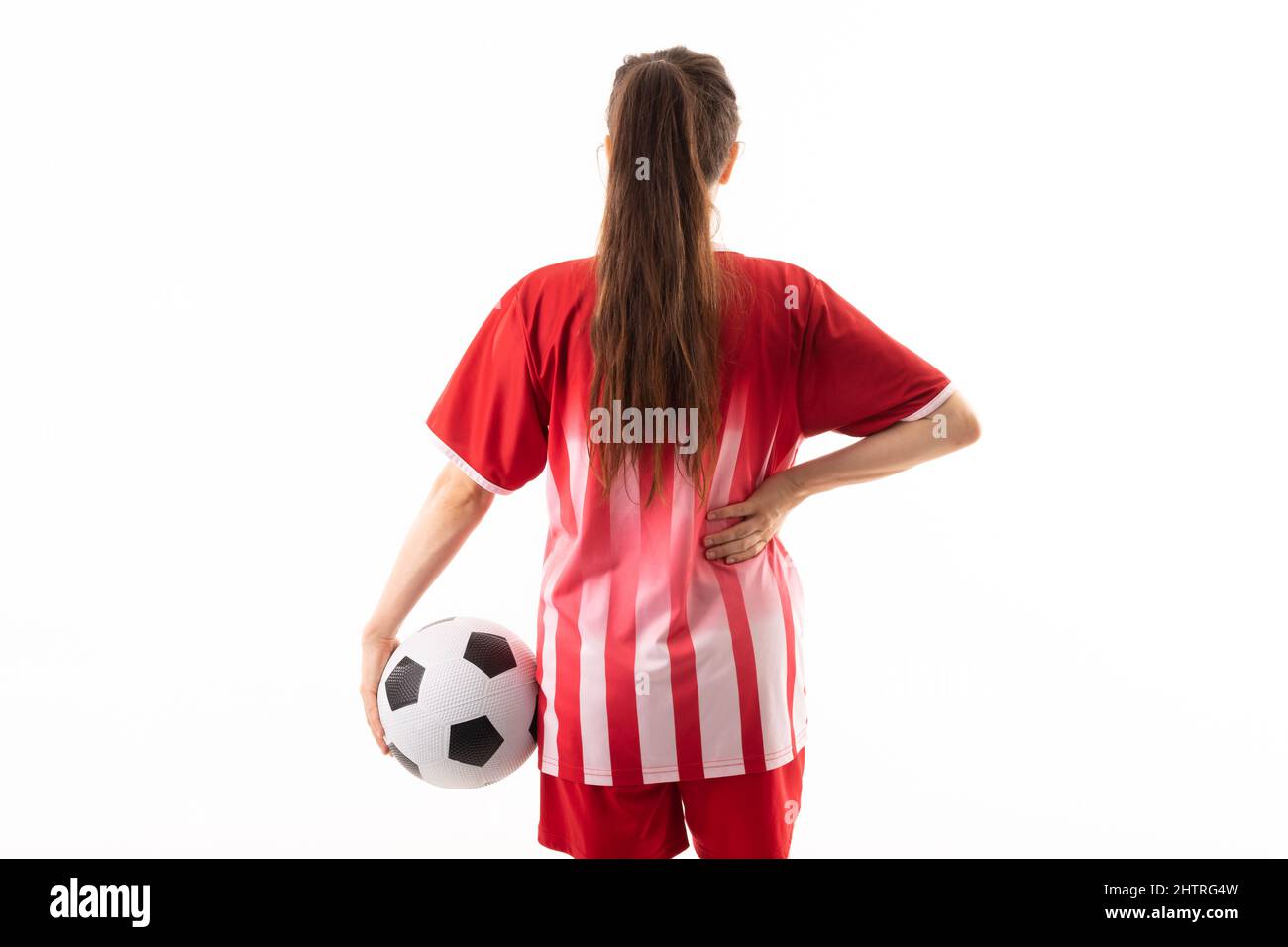Rear view of caucasian young female soccer player with ball and hand on ...