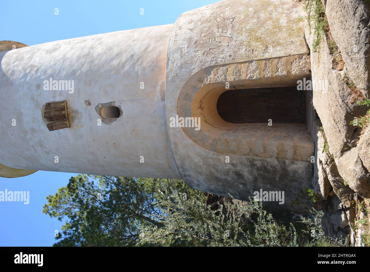 A vertical shot of an old lighthouse white tower with an arch gate with ...