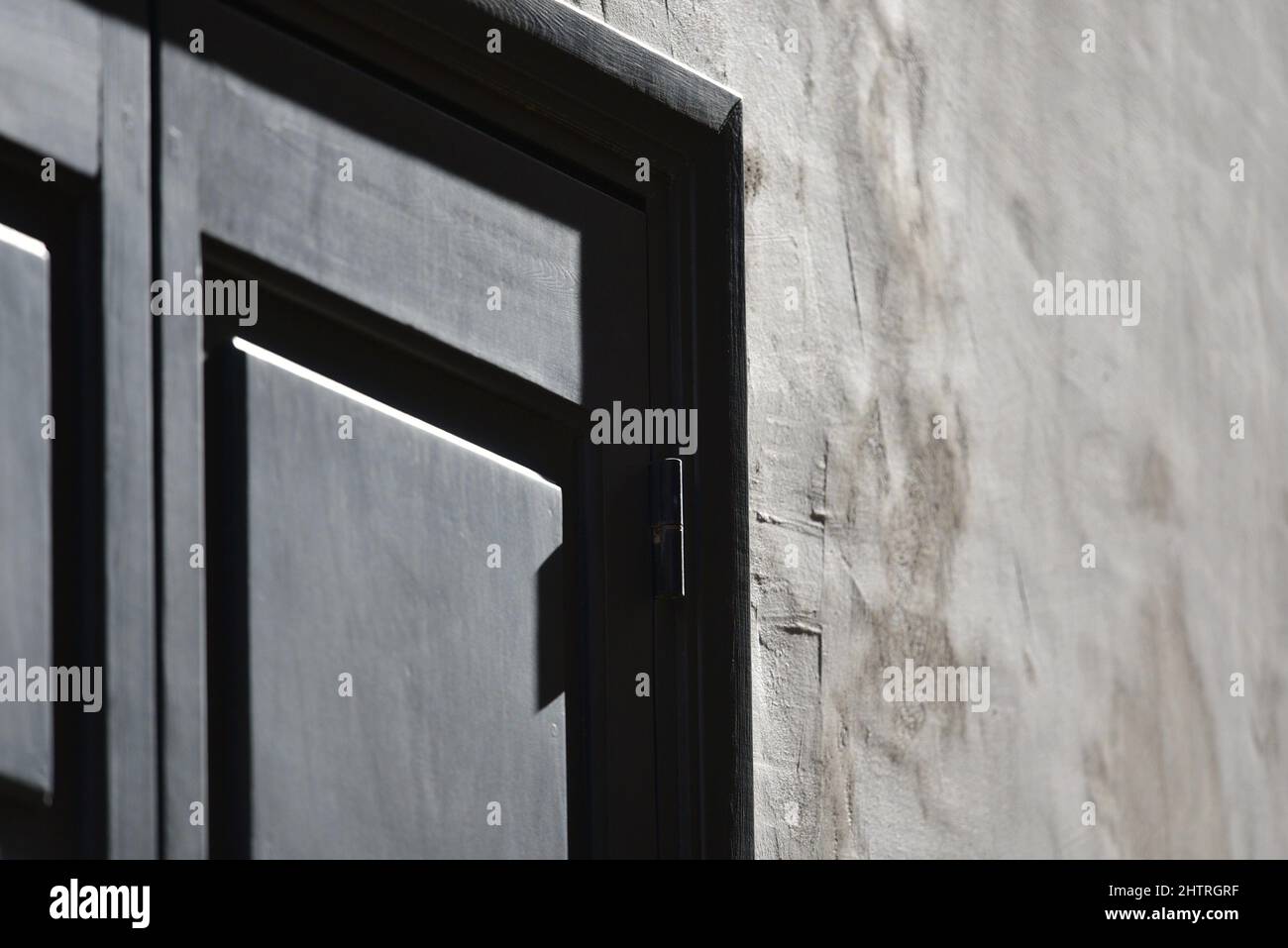 Charcoal grey wooden window shutters against a textured whitewashed ...