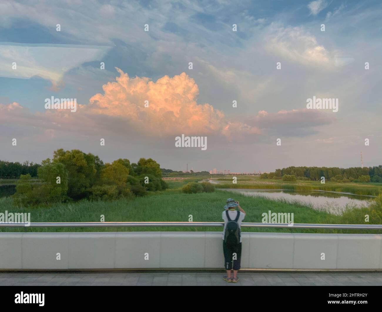 Photo of a man standing next to an outdoor railing and watching the ...