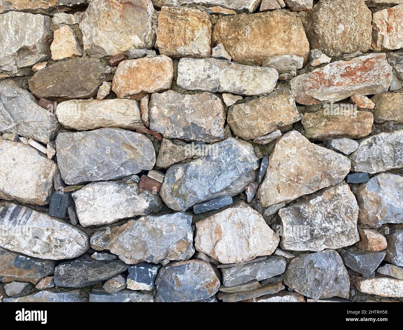 The stone wall. Asymmetrical stone wall made by hand. Close up and ...