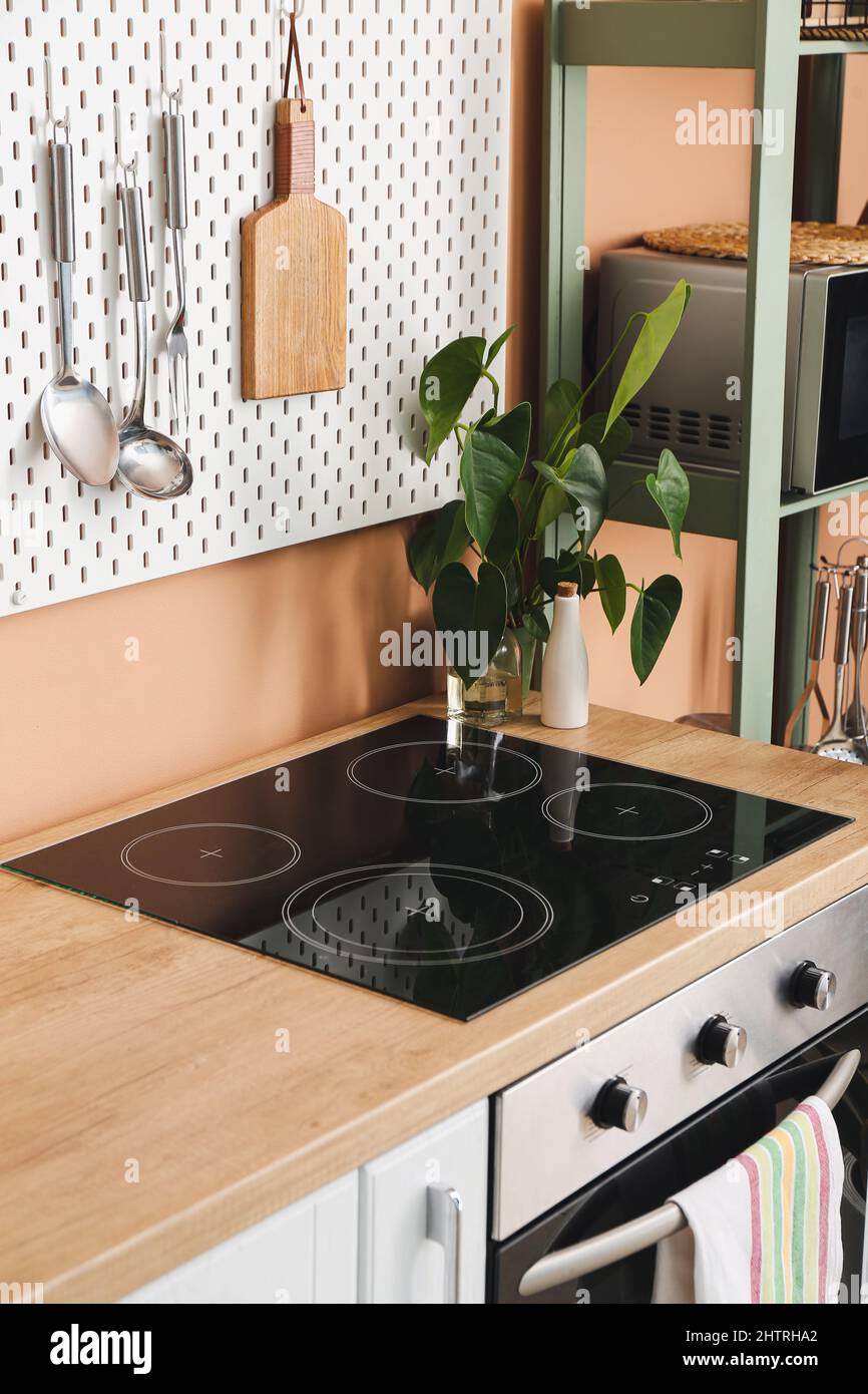 Modern electric stove on counter and pegboard with kitchen utensils on ...