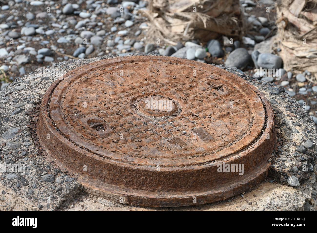 a rusty drainage man hole cover rusted in place, aged, weathered with a ...