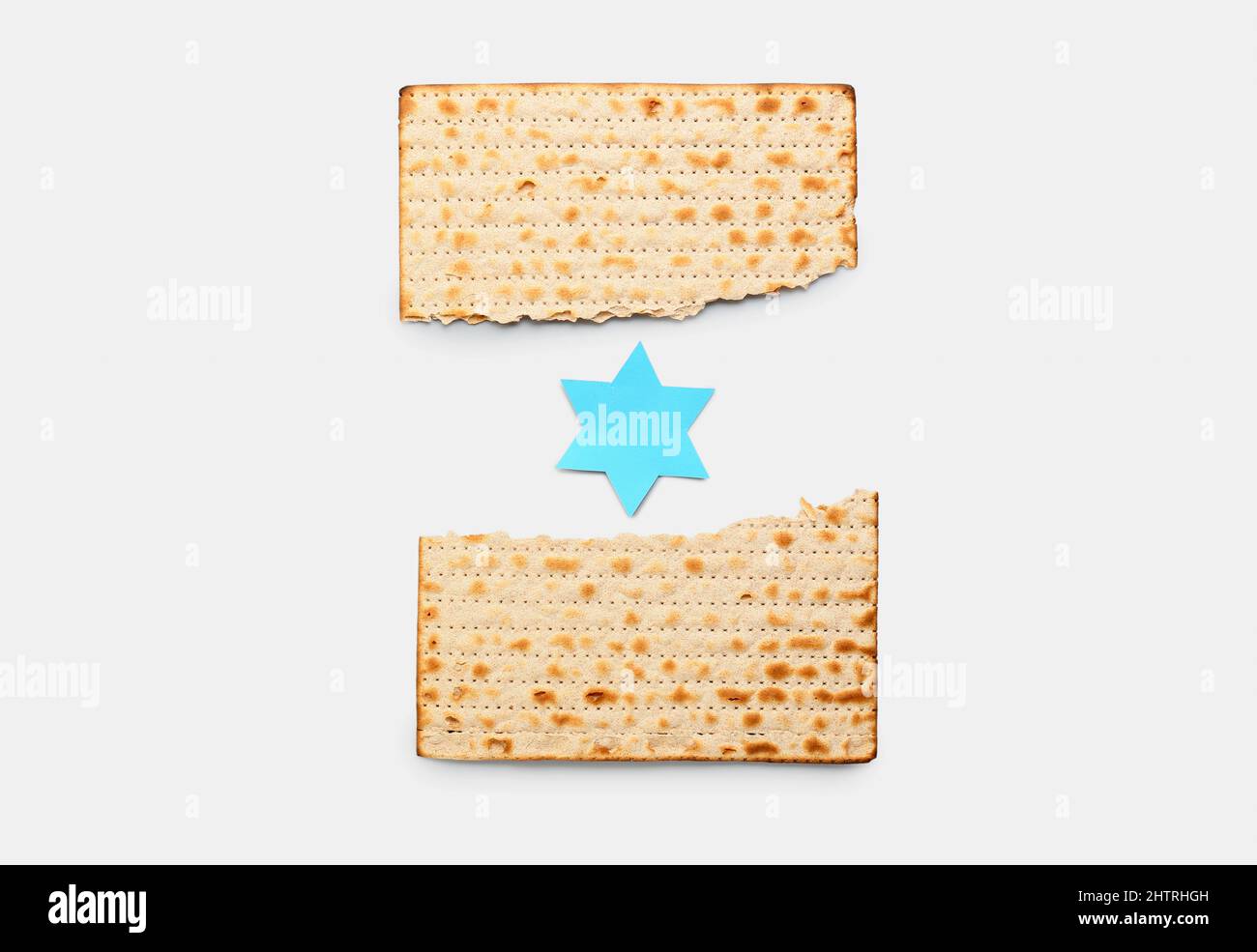 Torn Jewish flatbread matza for Passover with paper David star on light ...