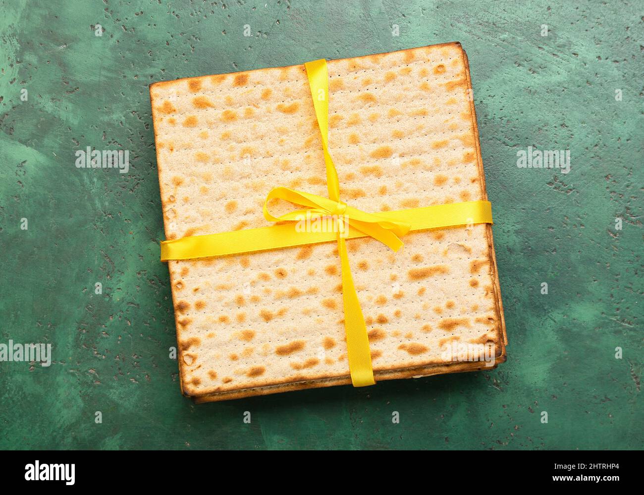 Jewish flatbread matza for Passover with ribbon on green background ...