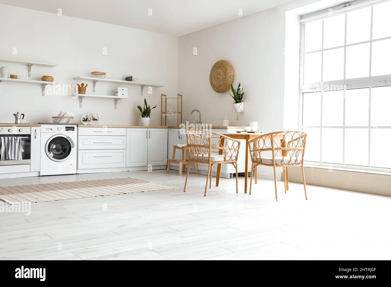 Interior of light kitchen with washing machine, white counters and ...