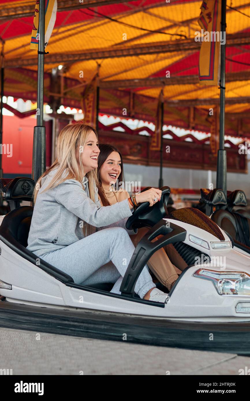 Two young women drive a bumper car while they are smiling Stock Photo ...
