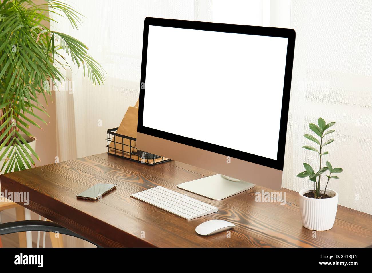 Stylish workplace with modern computer and mobile phone in light room ...