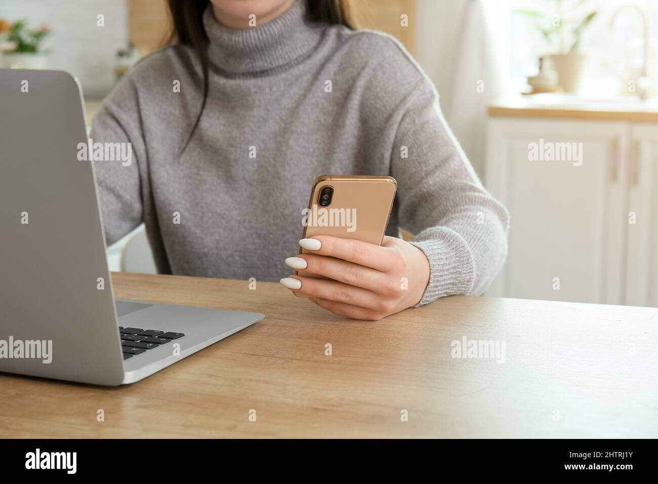 Woman using mobile phone on wooden table with modern laptop Stock Photo ...