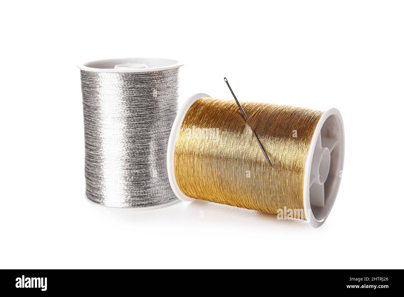 Silver and golden thread spools with needle on white background Stock ...