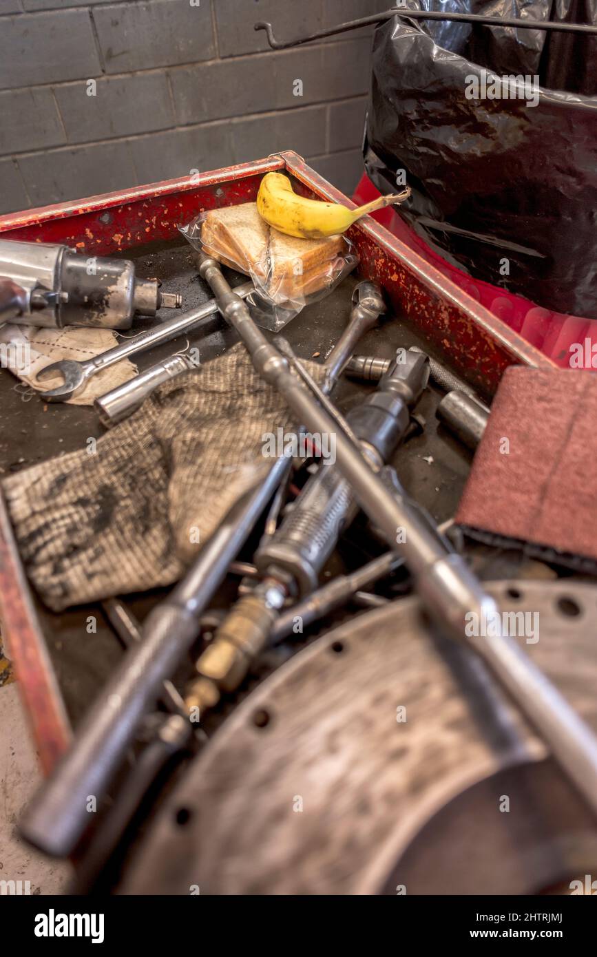 work station of a mechanic with several tools a sandwich and a banana ...