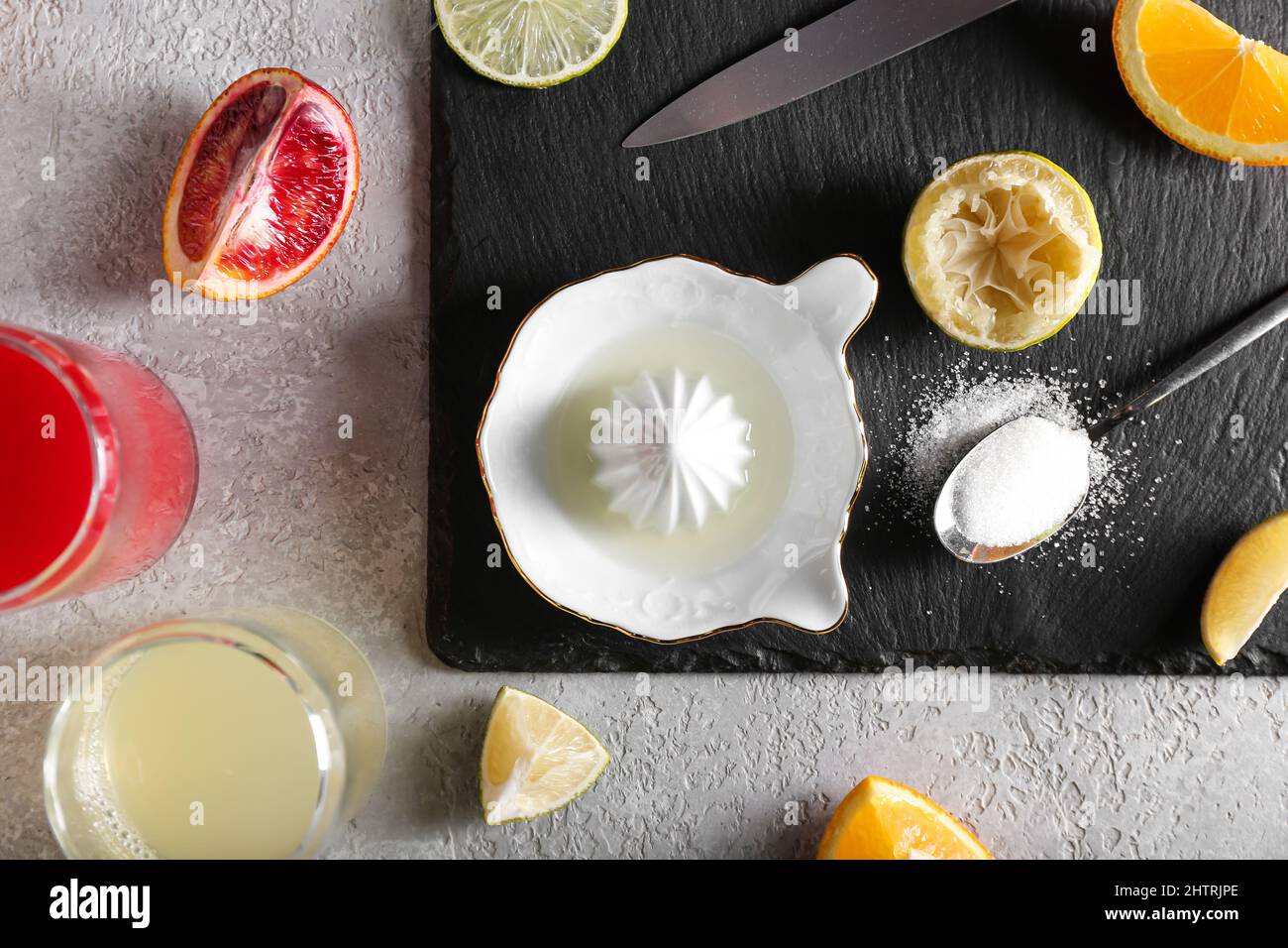 Ceramic juicer, juice, sugar and citrus fruits on grey background Stock ...