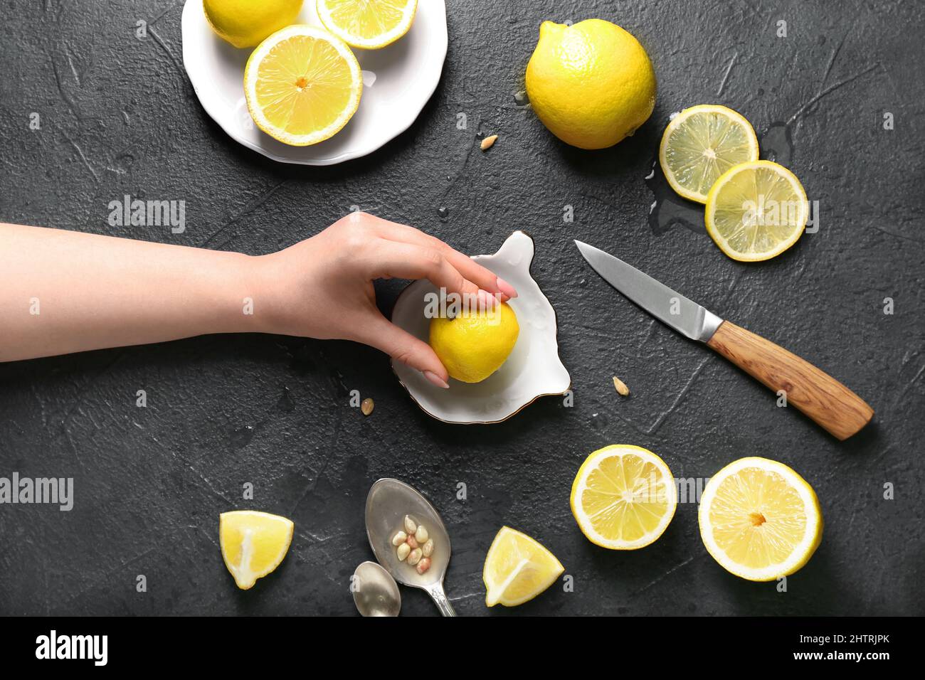 Woman squeezing fresh lemon on dark background Stock Photo - Alamy