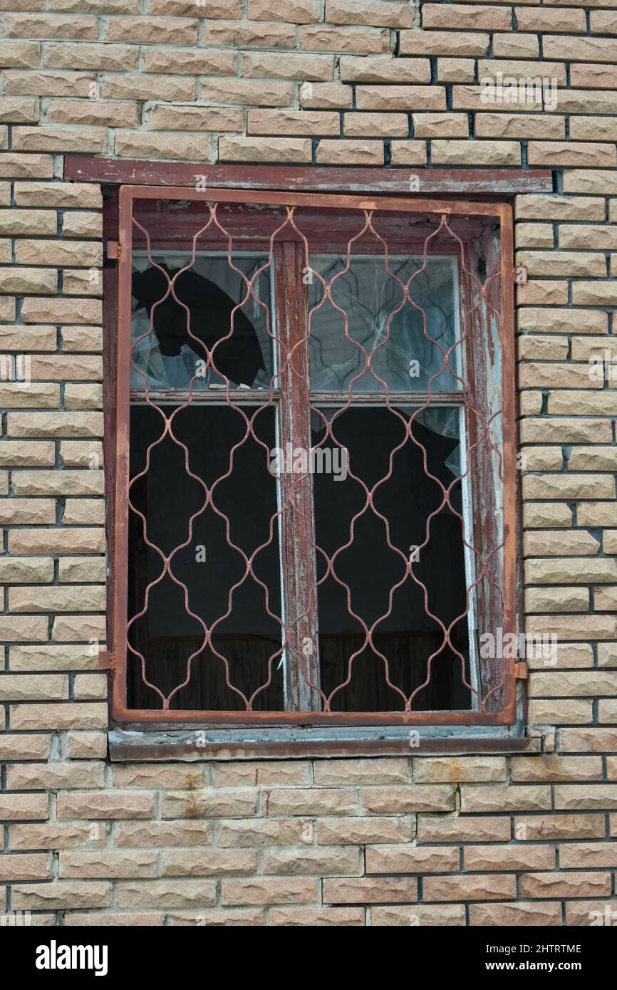 Broken glass window with an old wooden frame on a red brick wall of a ...