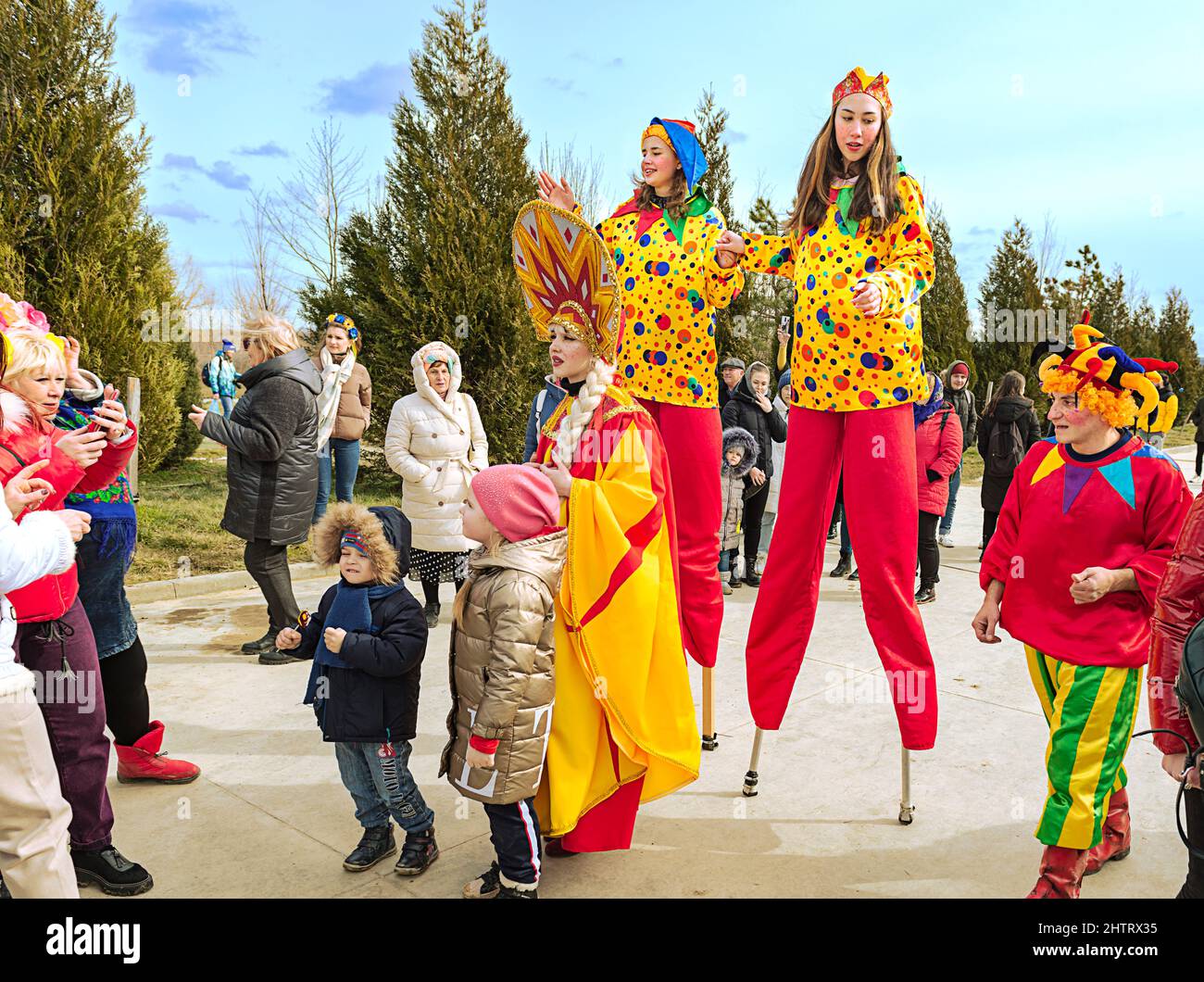 artists in costumes of buffoons on stilts during the celebration of ...