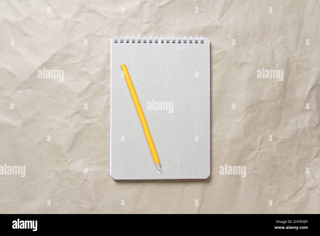 Gray notepad with white coiled spring and pencil on a background of ...